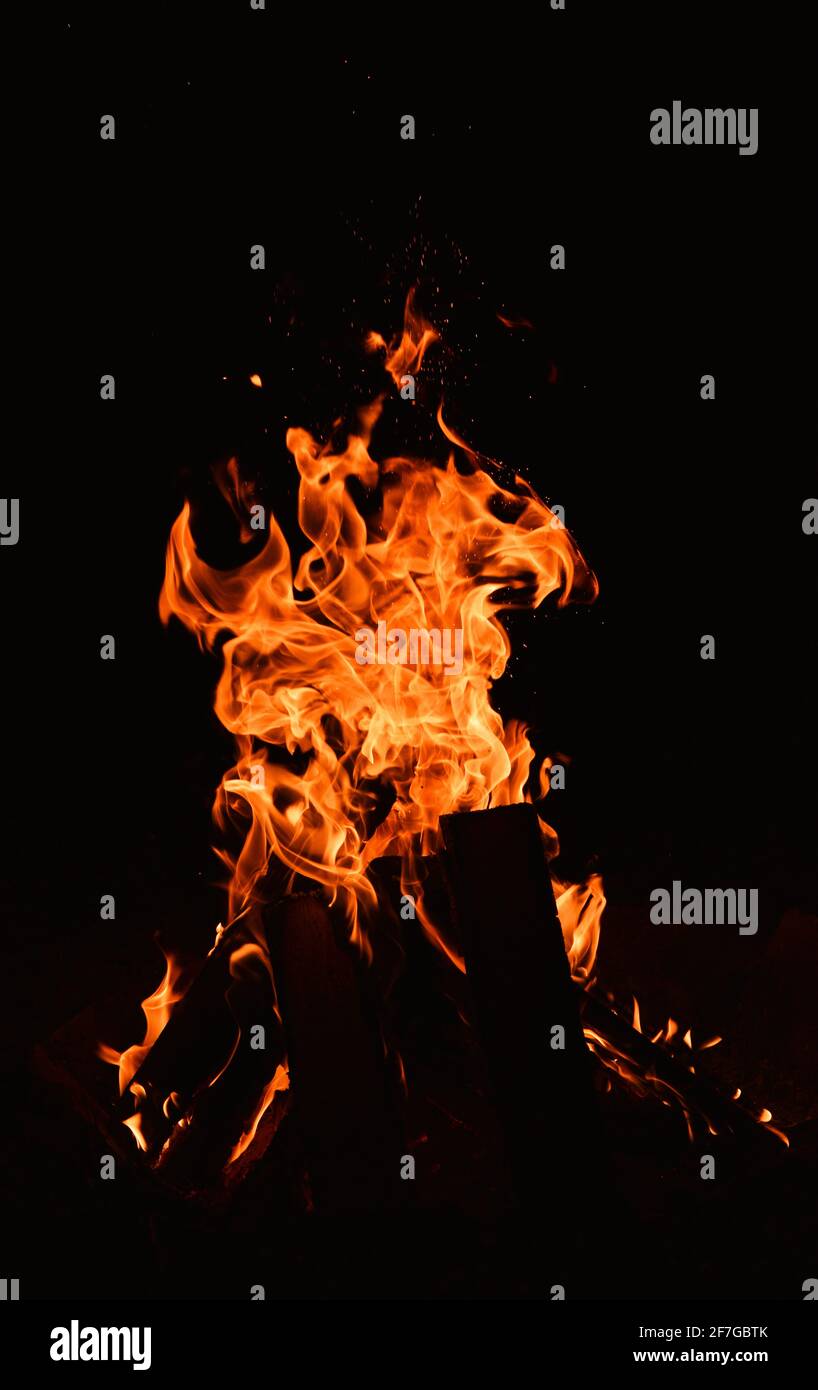 Real burning fire flames and flying hot fire sparks on black backround ...