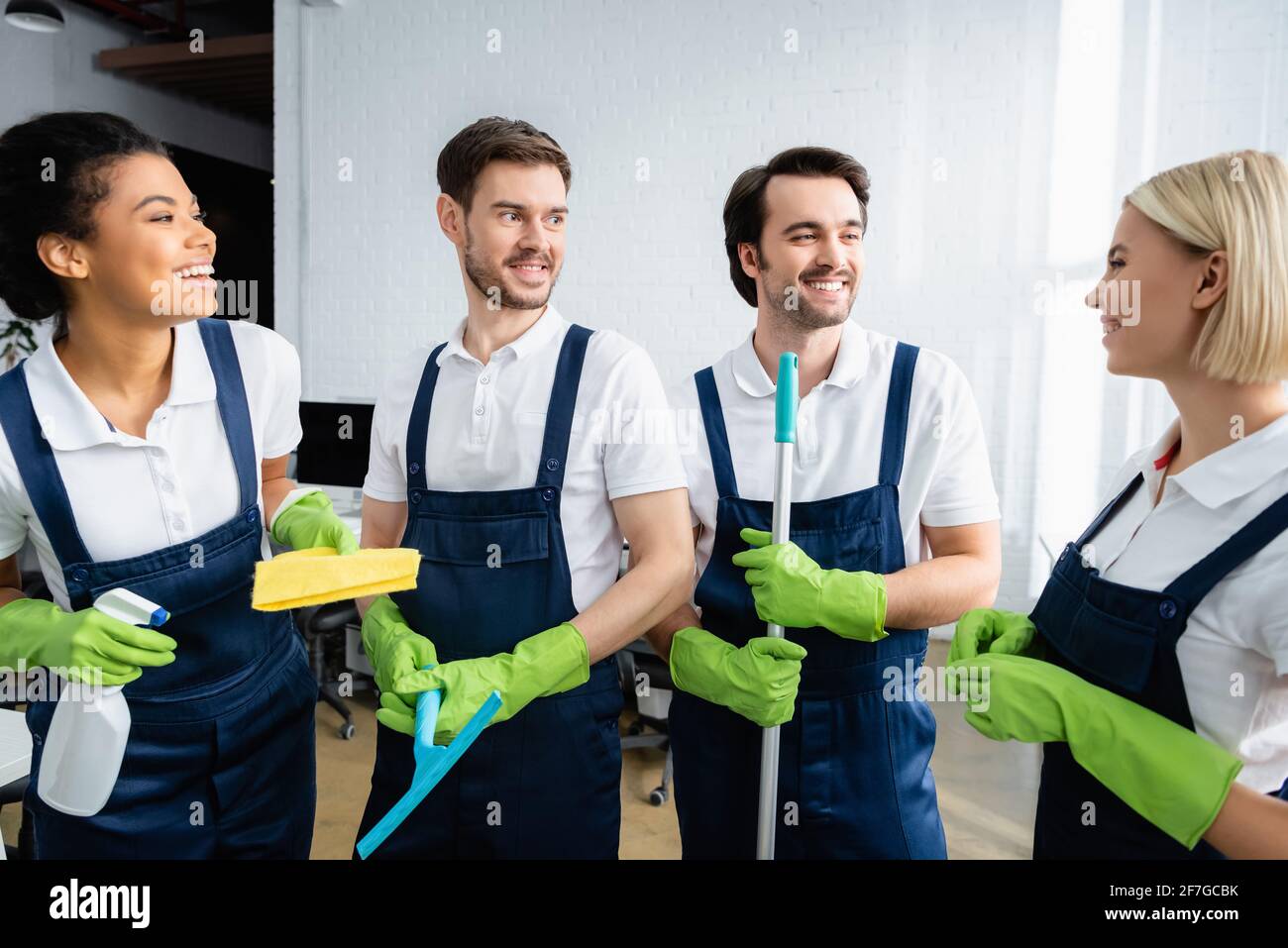 Positive multiethnic cleaners talking in office Stock Photo - Alamy