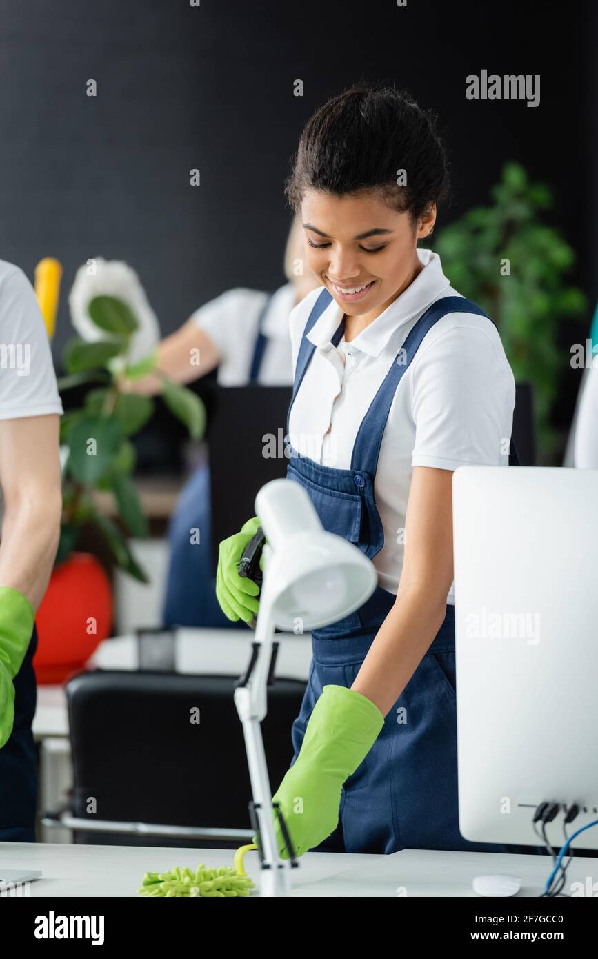 African american cleaner cleaning table and smiling in office Stock ...