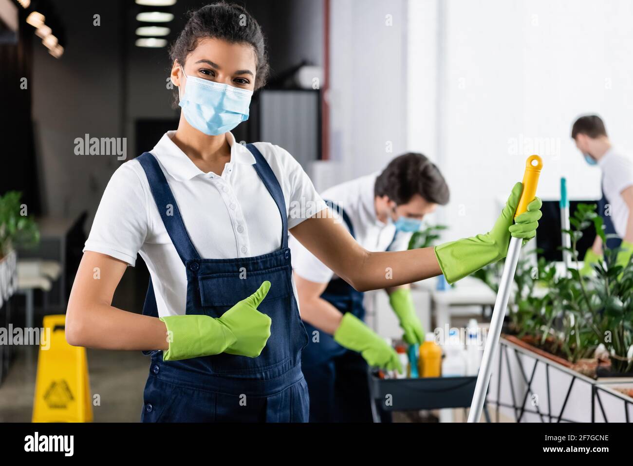 African american worker of cleaning company with mop showing like sign ...