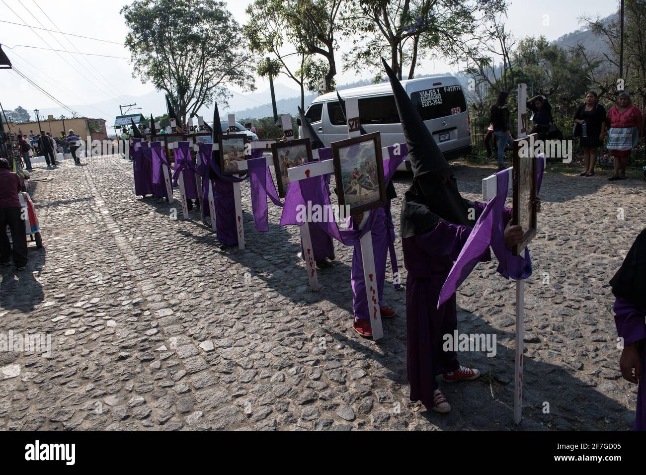 Hooded penitents carry crosses during Semana Santa procession in ...