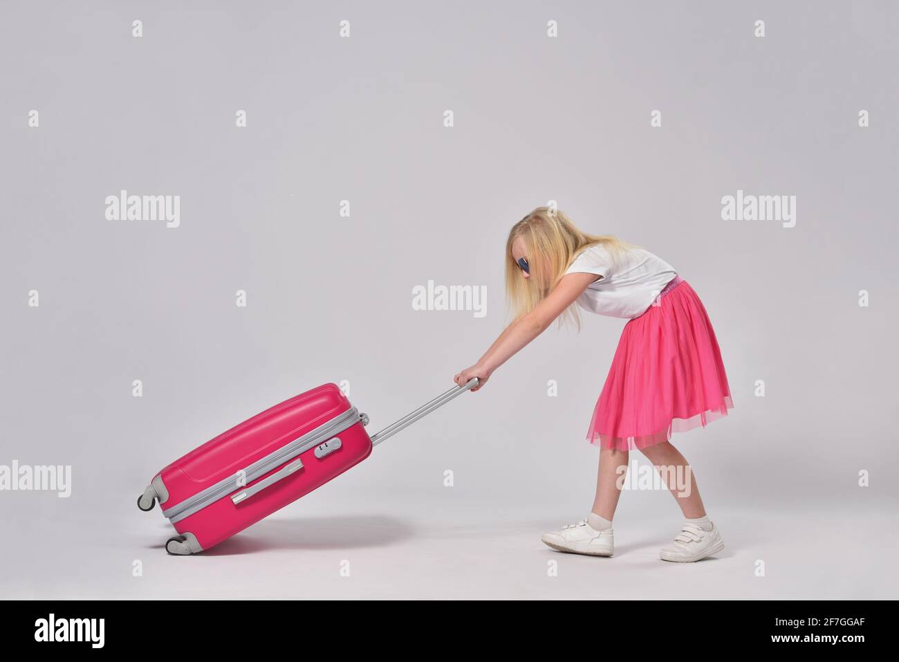 Teenage girl rolling her heavy suitcase Stock Photo - Alamy
