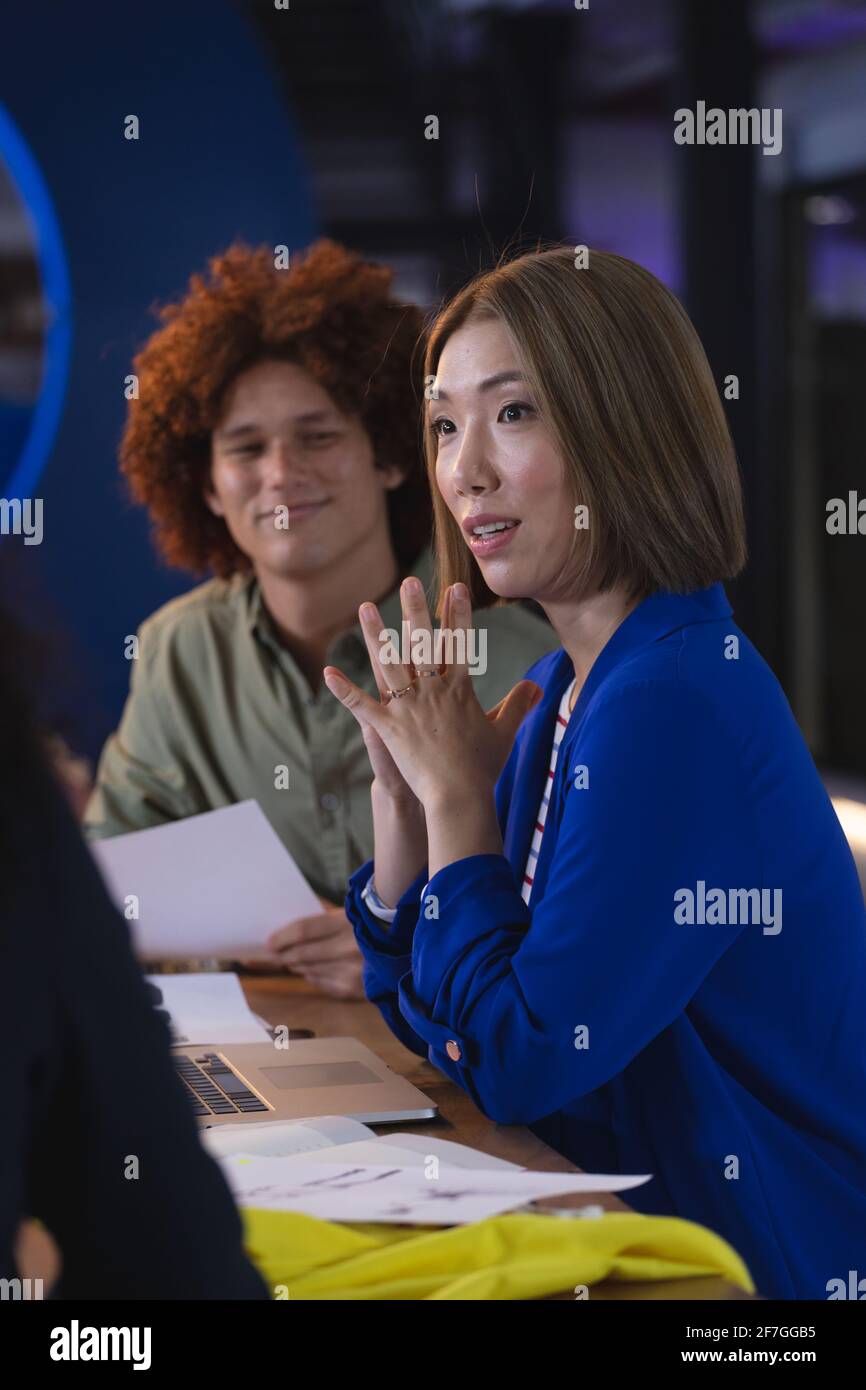 Asian businesswoman listening to group of colleagues during discussion ...
