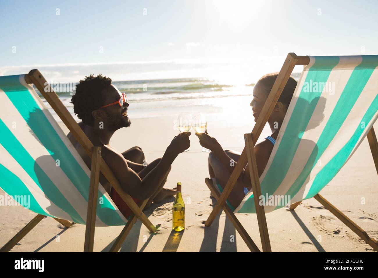 African American Couple In Love Sitting In Deckchairs Enjoying Drinks