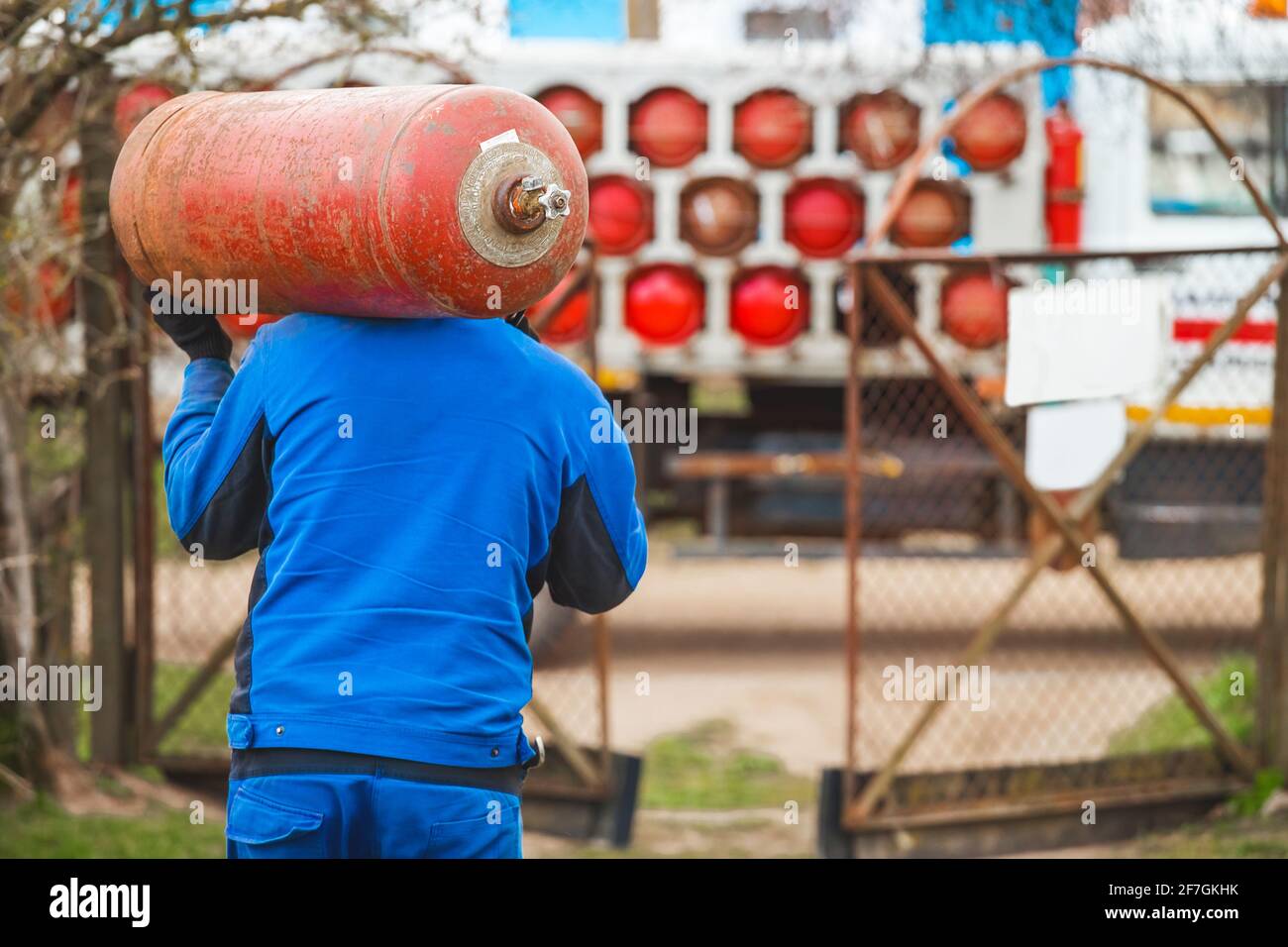 A male industrial worker walks with a gas cylinder to a gas car ...