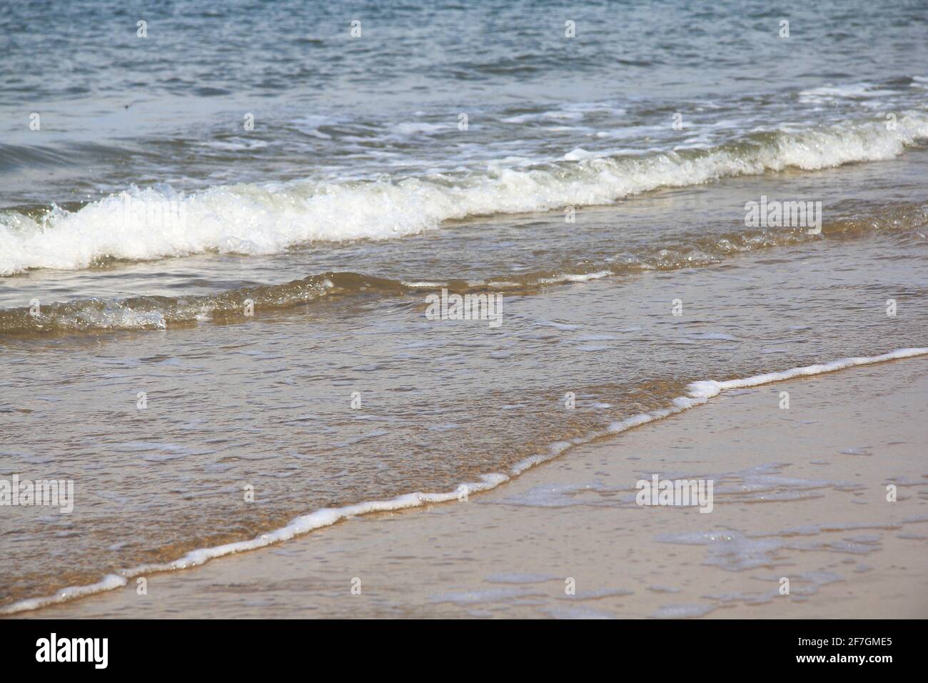 Waves with whitecaps flood the sandy beach Stock Photo - Alamy