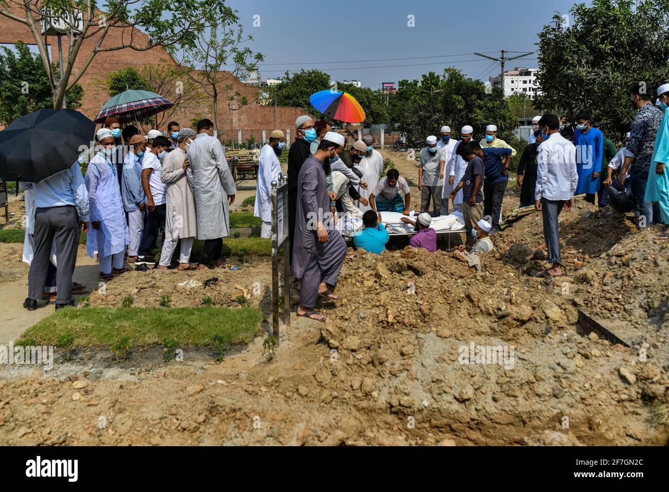 (EDITORS NOTE: Image depicts death)Relatives lower the body of a covid ...