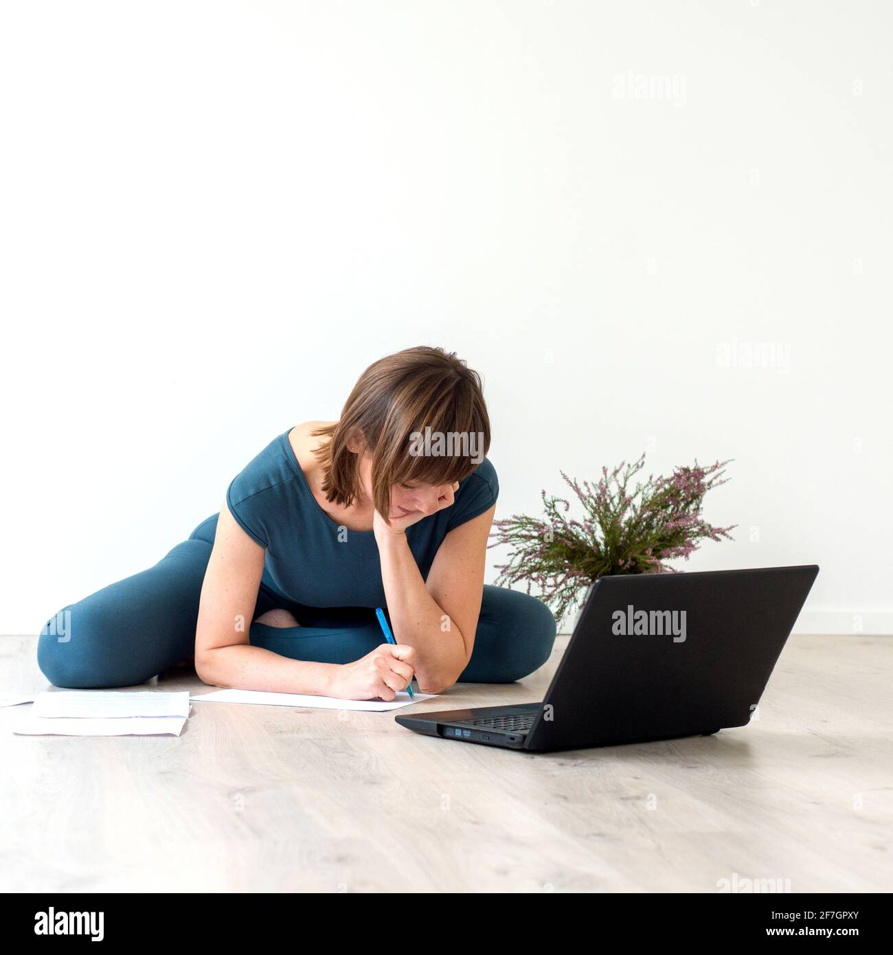 Woman sitting on the floor and writing on a piece of paper next to a ...