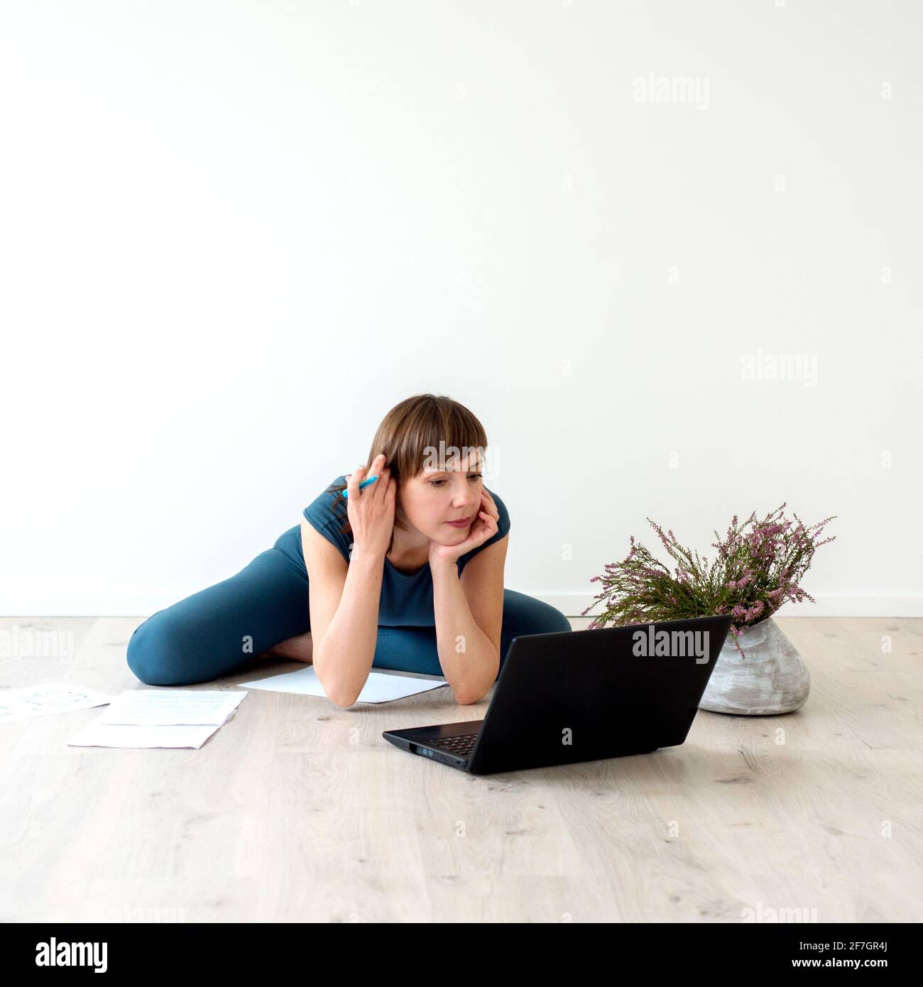 Woman sitting on the floor and writing on a piece of paper next to a ...