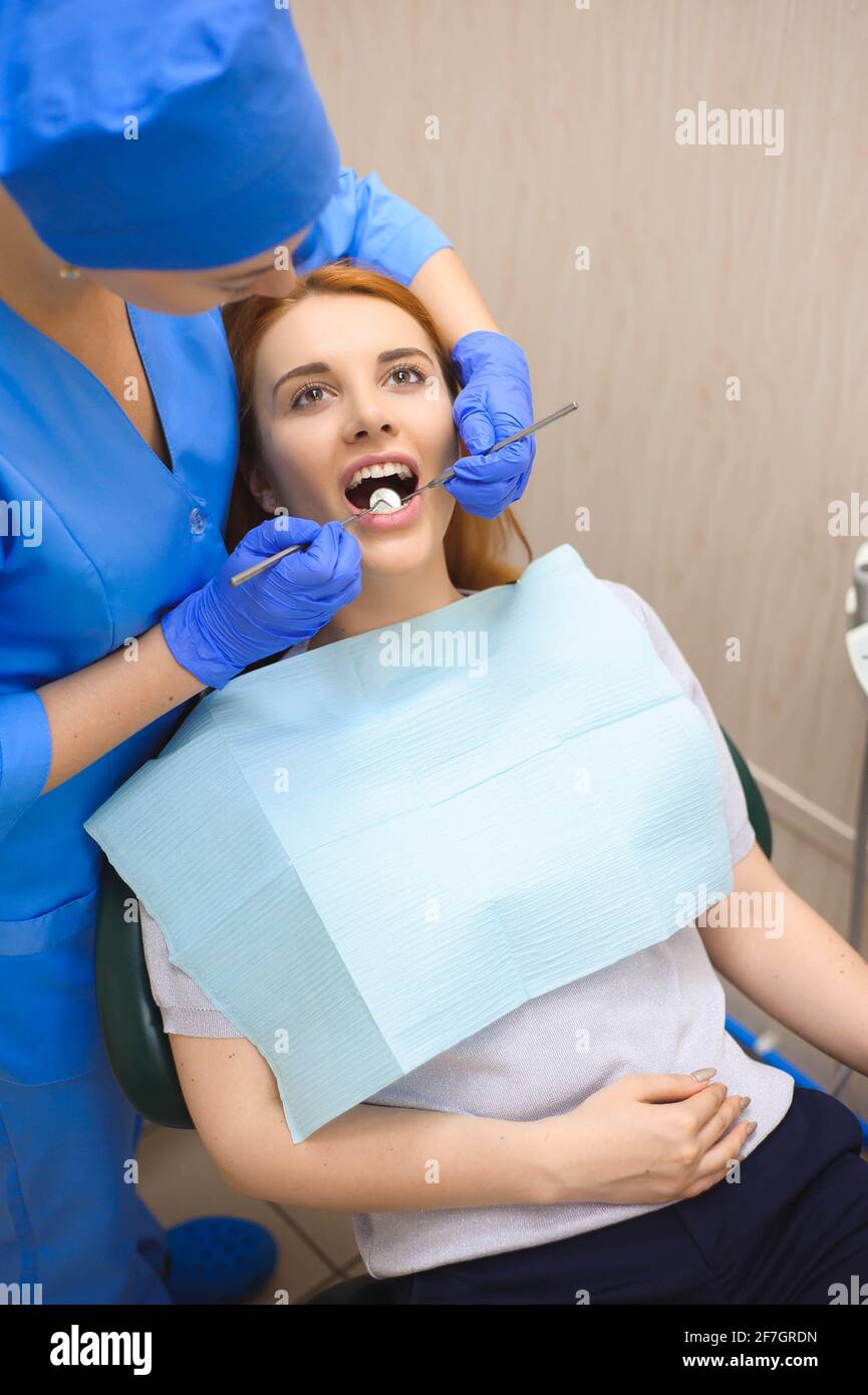 Doctor in uniform checking up female patient's teeth in dental clinic ...