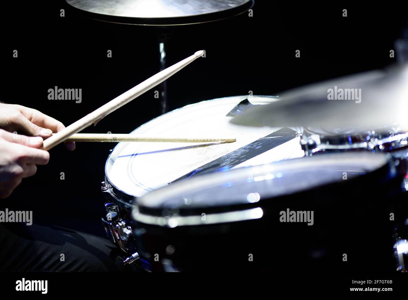 Man plays musical percussion instrument with sticks closeup on a black ...