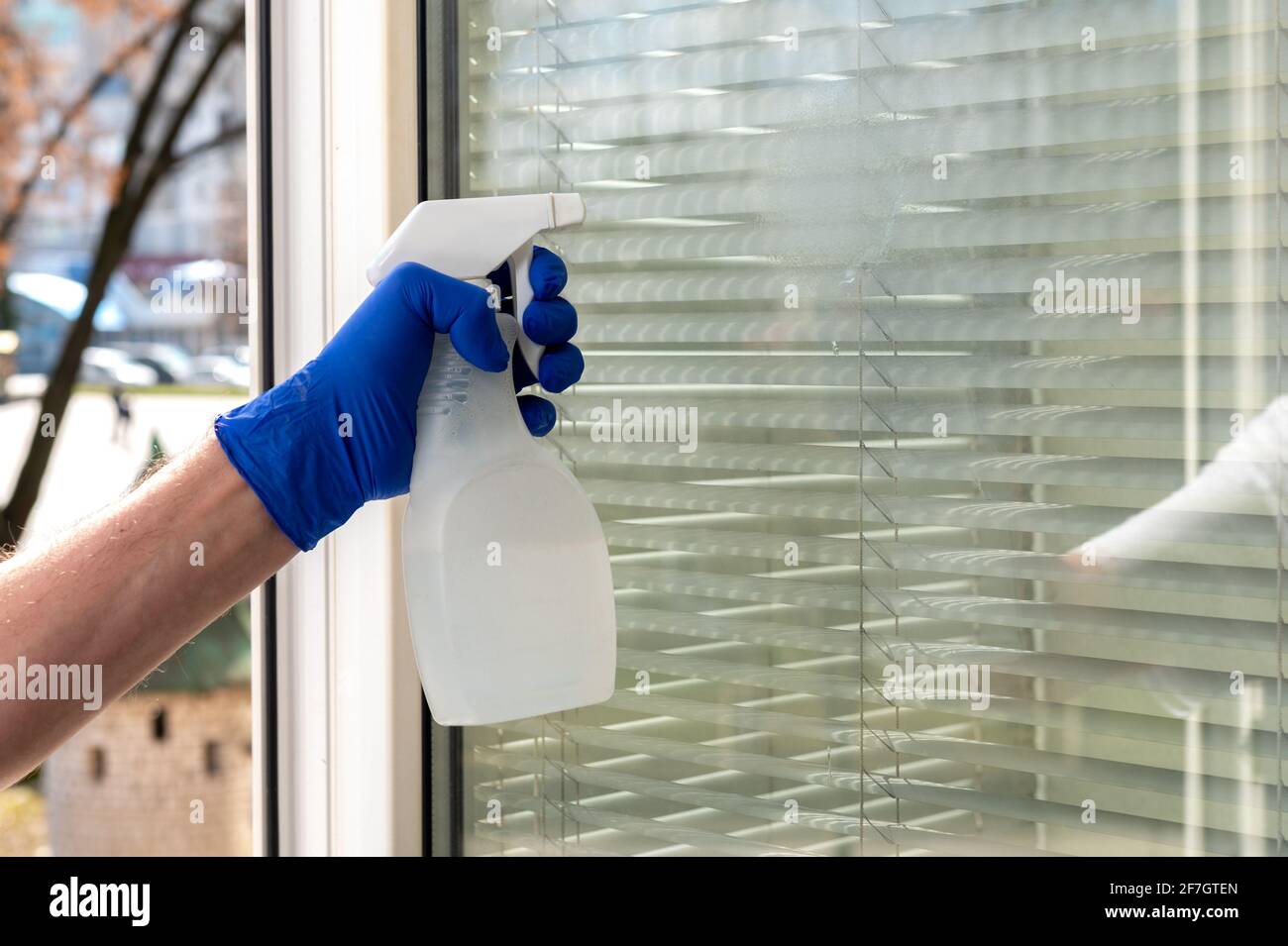 Gloved hand cleaning window with spray Stock Photo - Alamy