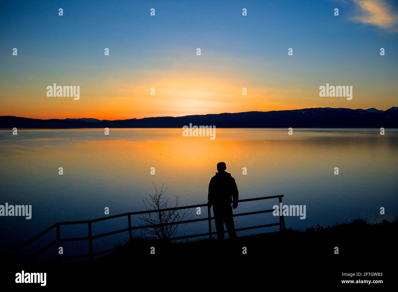Silhouette of a man watching the sunset in the distance above the ...