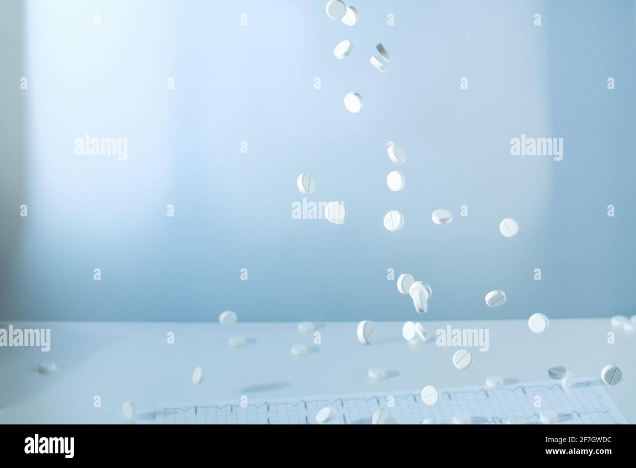 Tablets fall out on the blue table with an electrocardiogram lying on ...