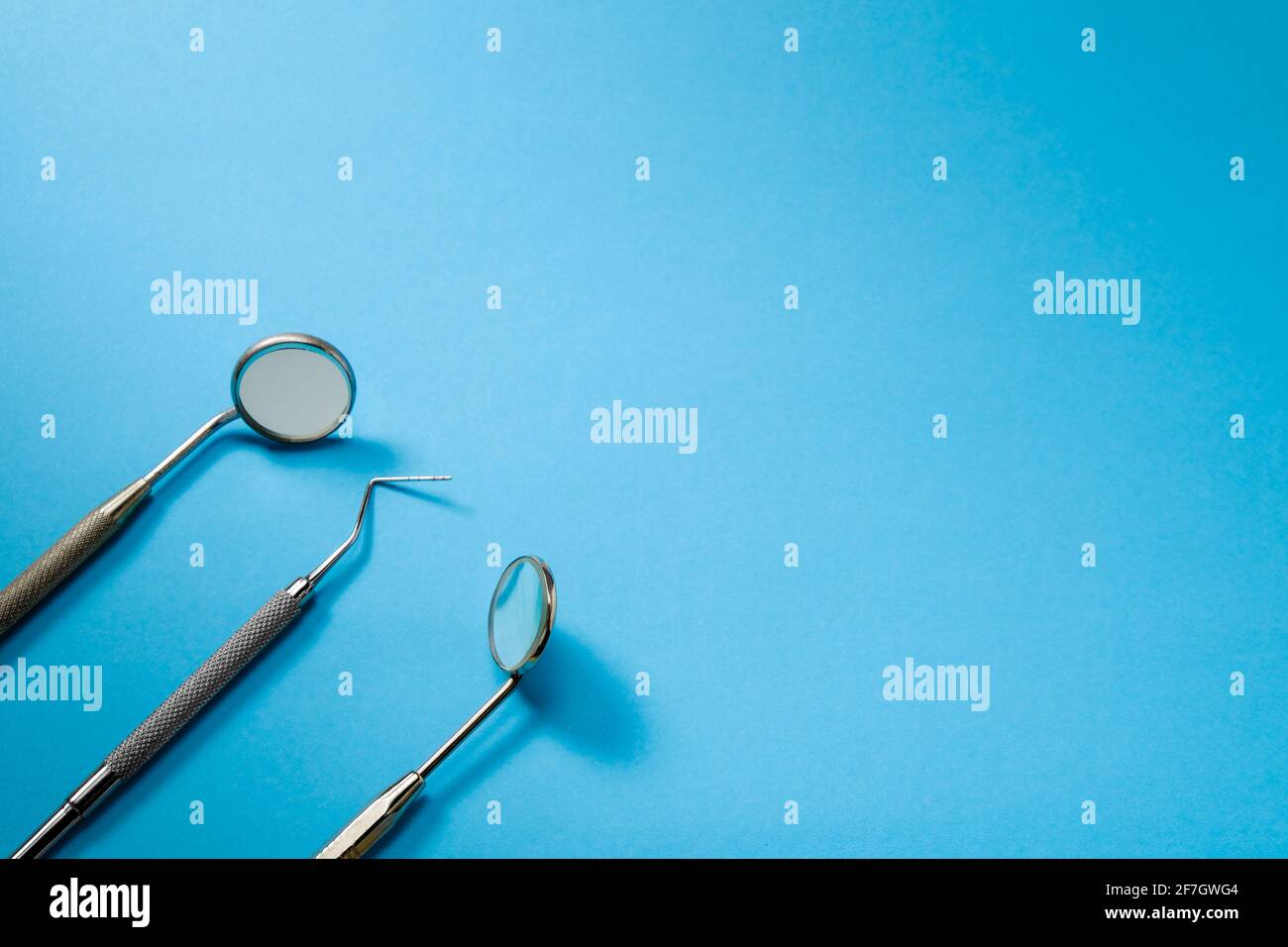 Dentist tools: mirror, dental explorer and tweezers lying on blue ...