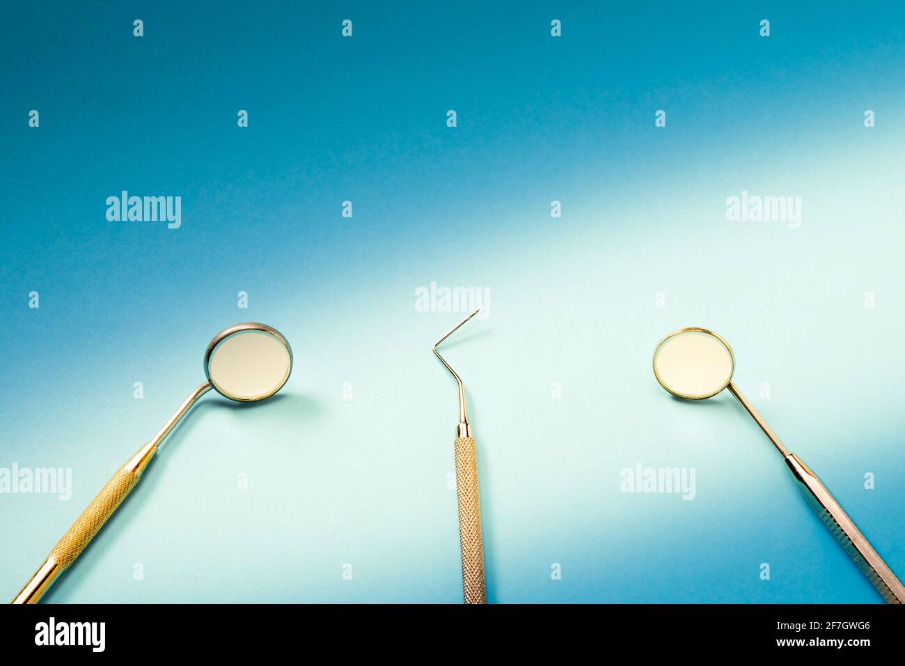 Dentist tools: mirror, dental explorer and tweezers lying on blue ...