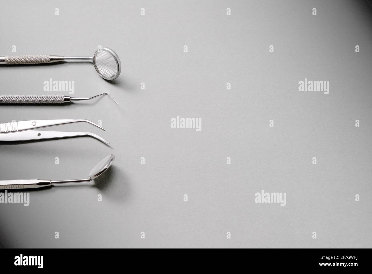 Dentist tools: two mirrors, dental probe and tweezers lying on gray ...