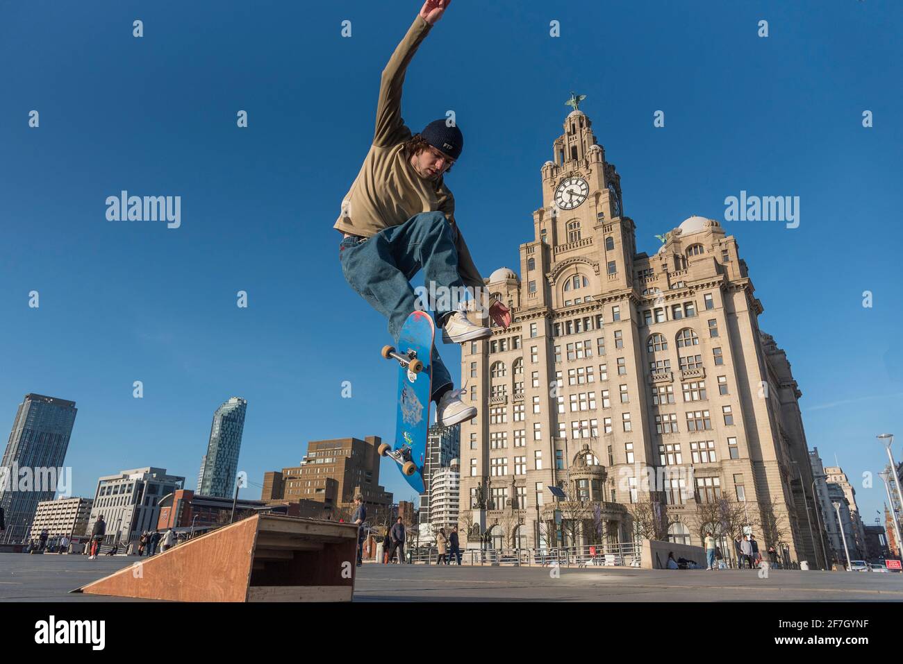 Skateboarders jumping at Liverpool Pierhead infront of the Royal Liver ...