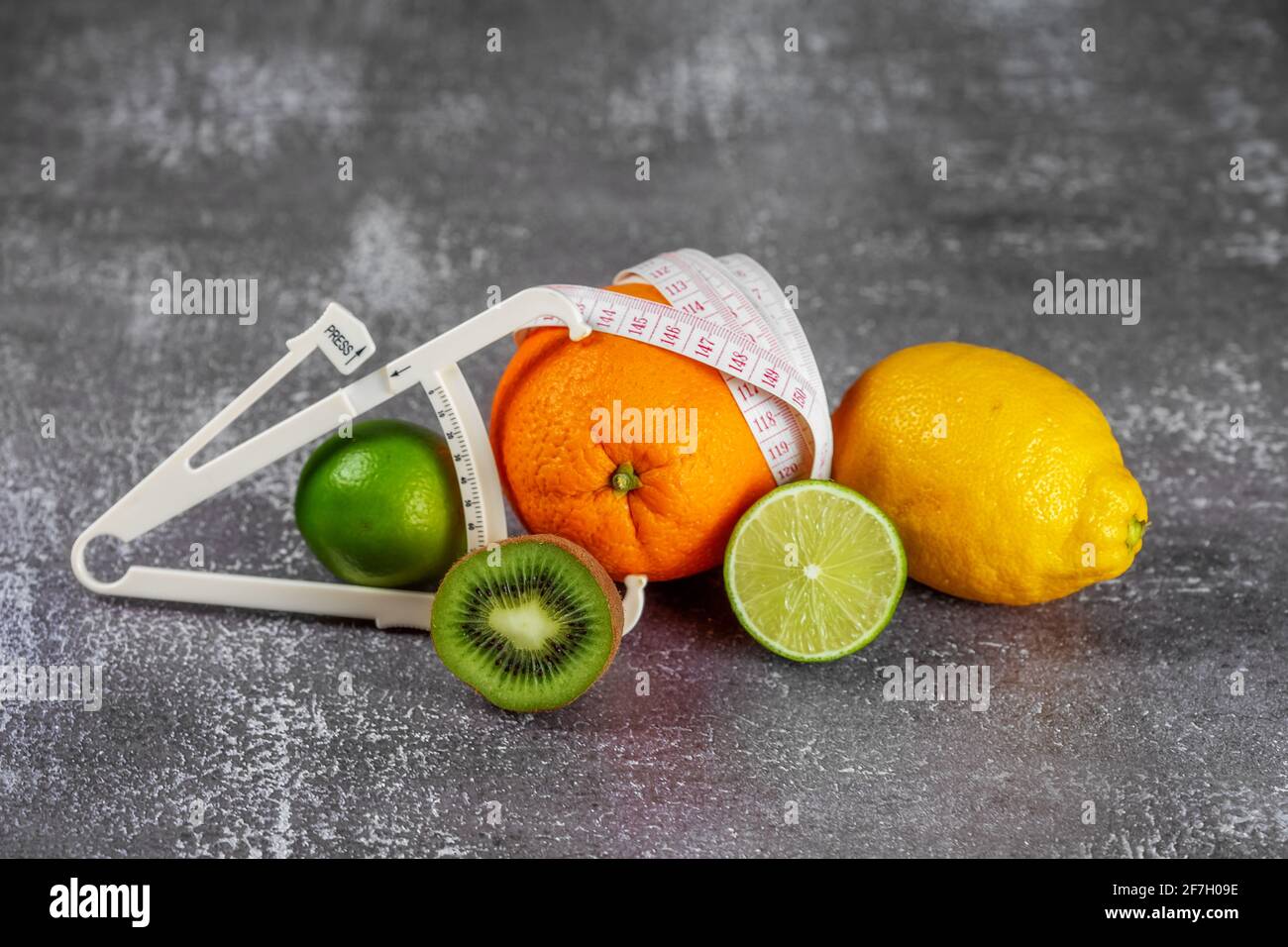 An orange wrapped with a measuring tape and a caliper surrounded by ...