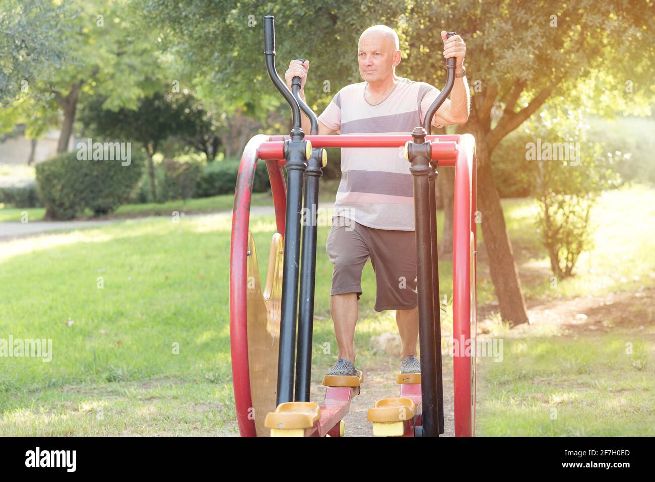 Happy older man working out on the sports public equipment in the ...