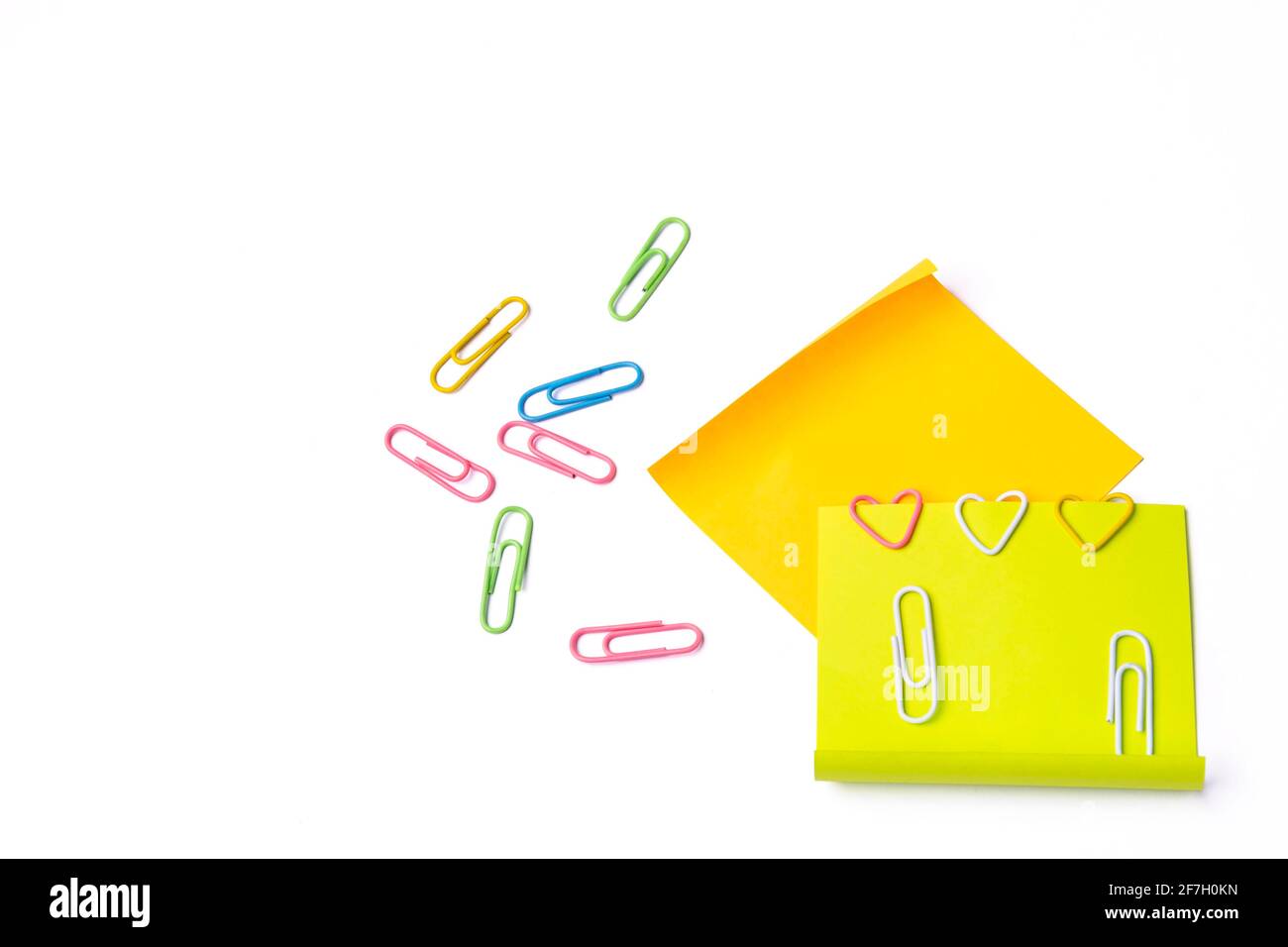 Paper clips in shape of heart on fluorescent sticky notes on white ...