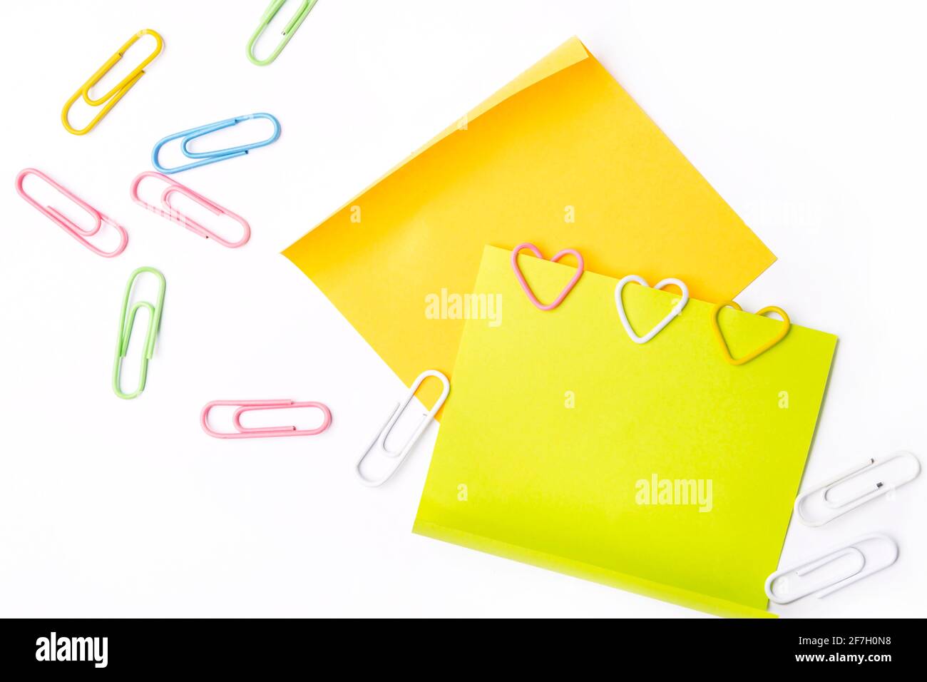Paper clips in shape of heart on fluorescent sticky notes on white ...