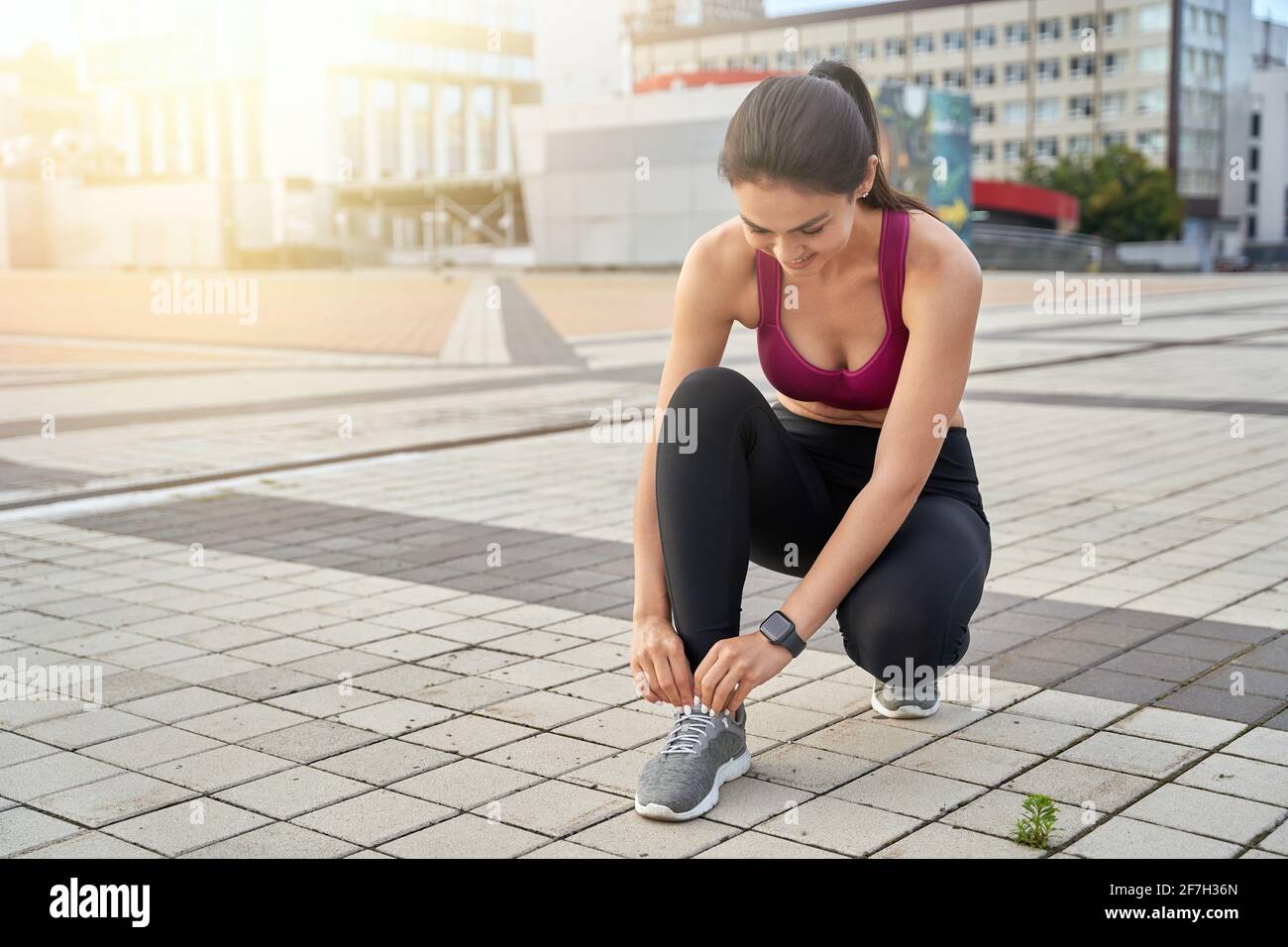 Athletic lady squatting and tying laces on sneakers Stock Photo - Alamy