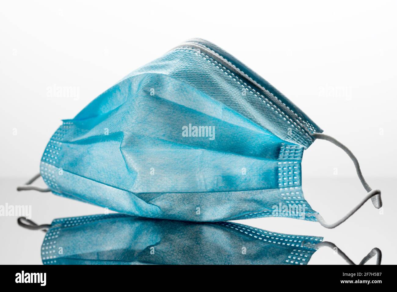 Surgical mask with rubber ear straps. A typical three-layer surgical ...