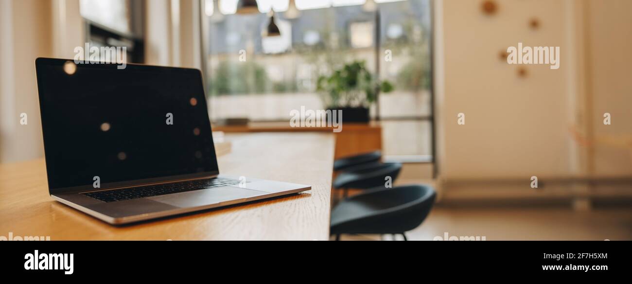Laptop on board room table. Panorama view of office space with laptop ...
