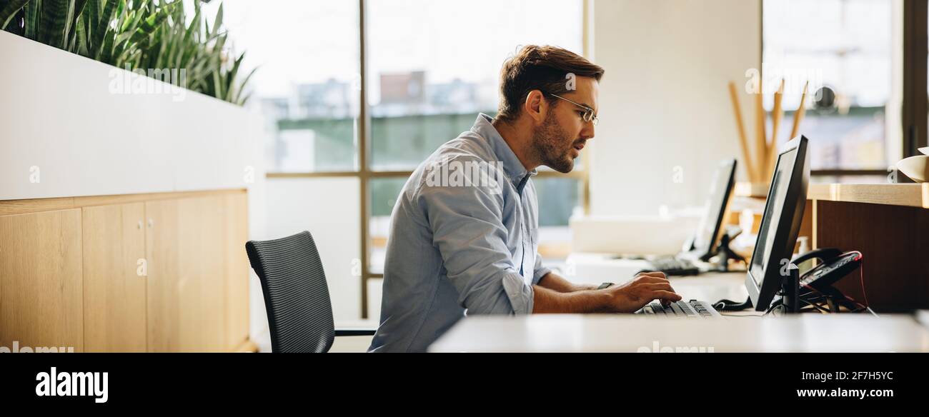 Freelancer looking at computer screen while typing. Young businessman ...