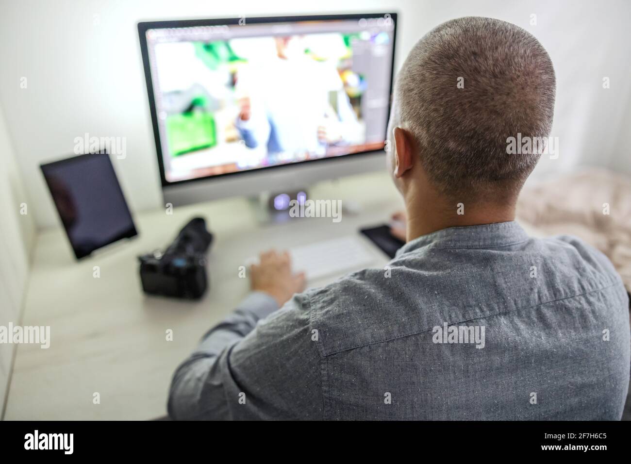 Man with gray hair is sitting in front of a computer at a work desk ...