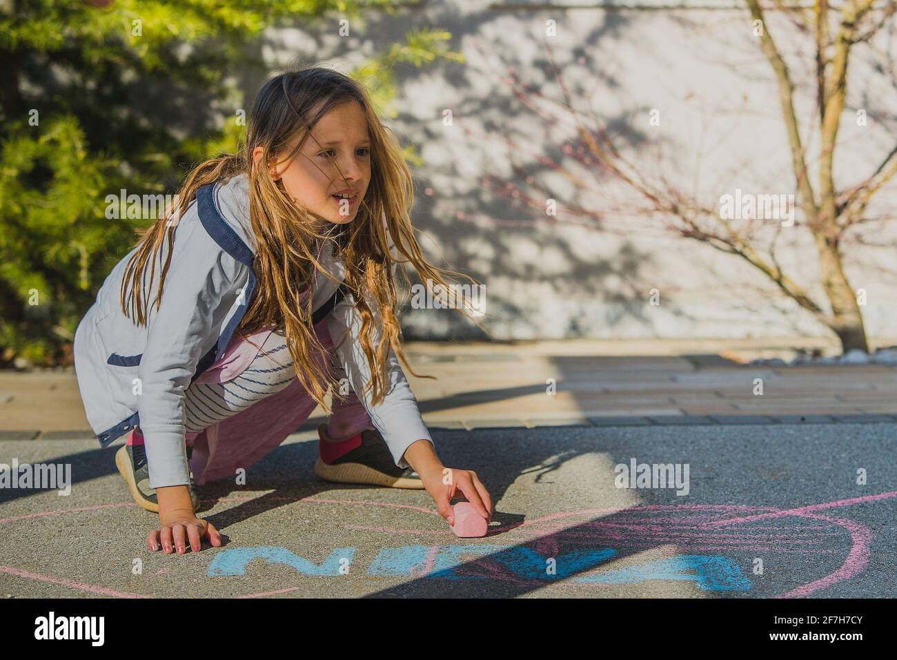 Little blonde girl squatting on the floor and drawing a picture with a ...