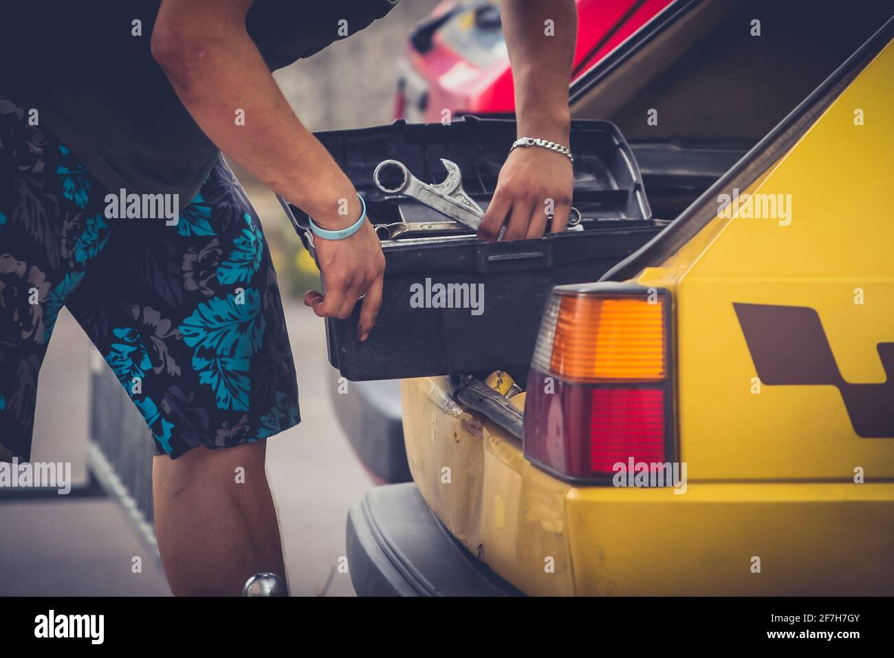 Hands of a person taking out the tools from a tool box in a trunk of an ...