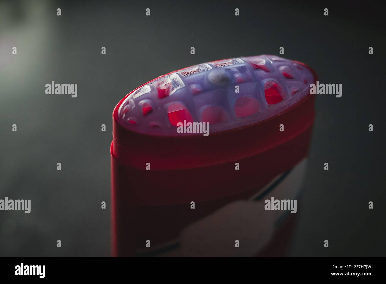 Detail of empty red deodorant stick with open top on a gray background ...