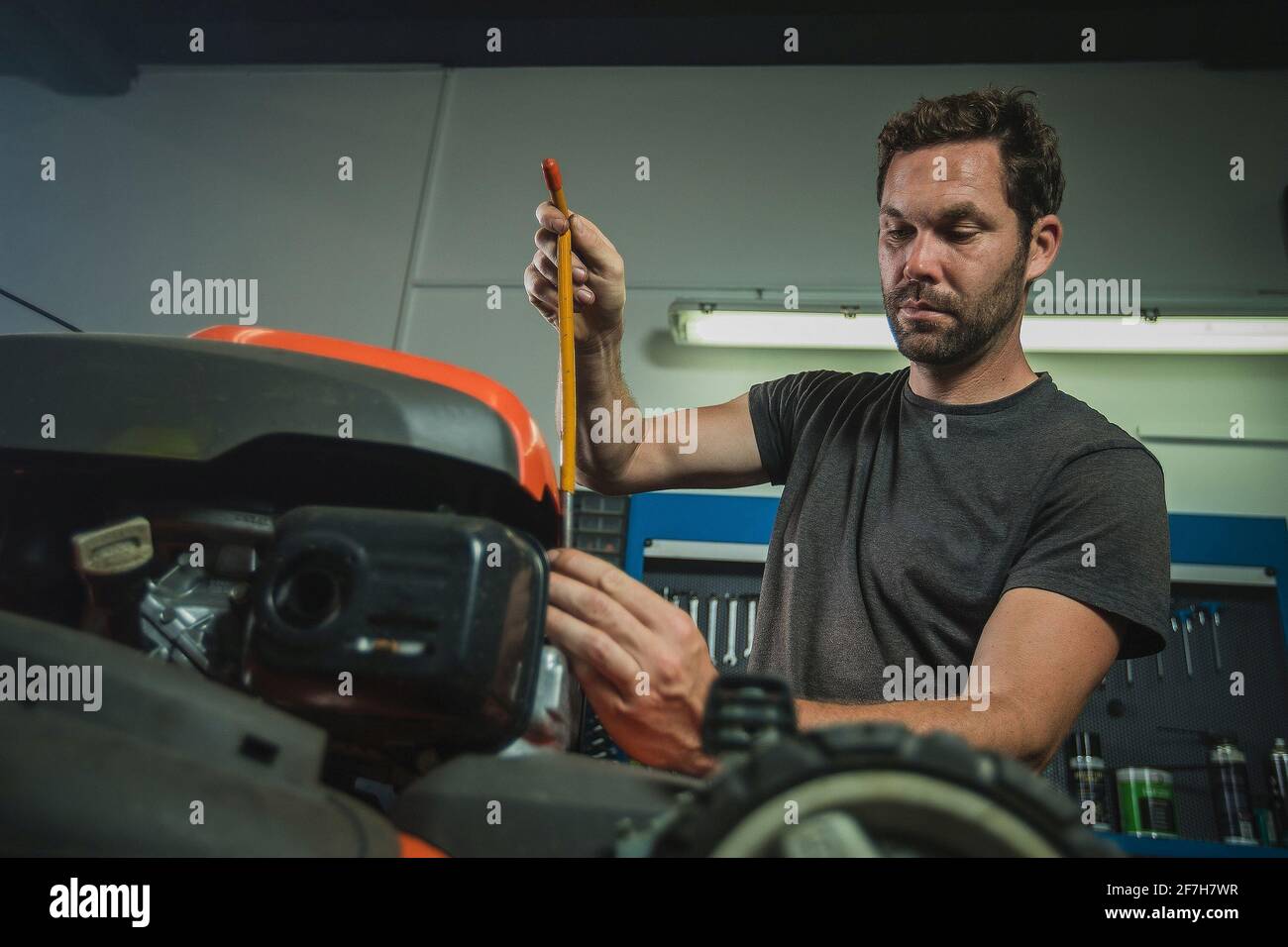 Professional serviceman is repairing a lawnmower, unscrewing a spark ...