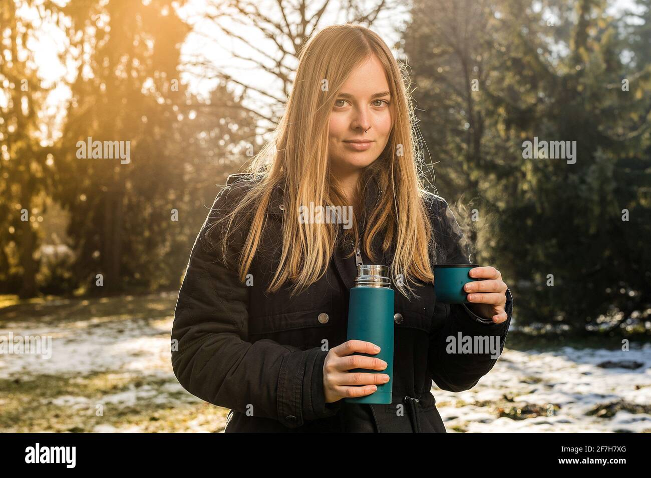 Cute blonde girl with long hair and septum piercing is drinking tea ...