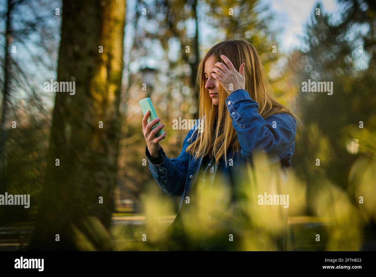 Cute blonde girl with long hair, septum piercing and jeans shirt using ...