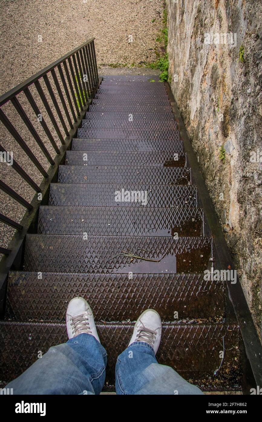 A person in jeans and white sneakers is standing on top of the metal ...
