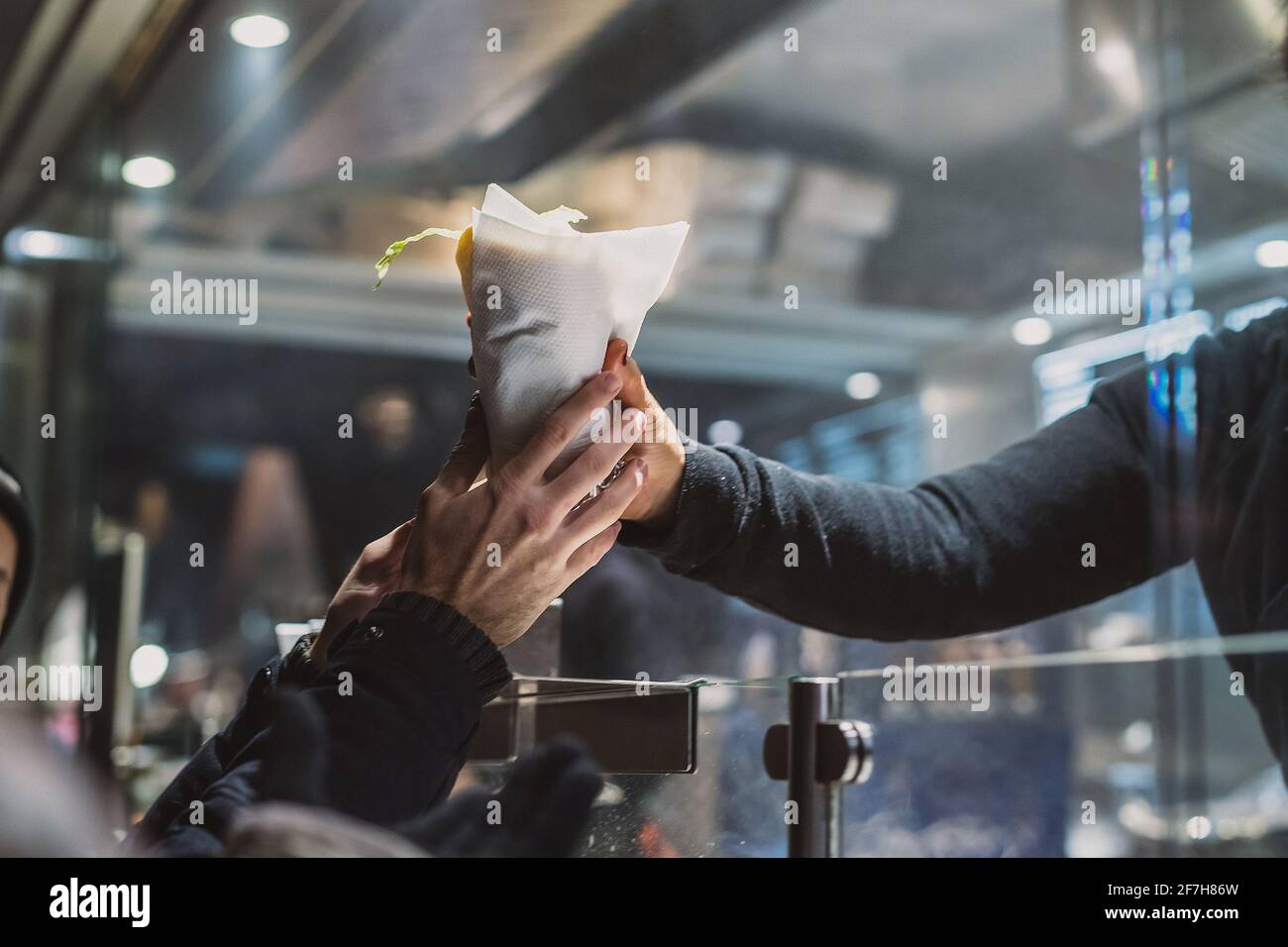 Person receiving a fresh kebab or gyros in a fast food stall or vendor ...