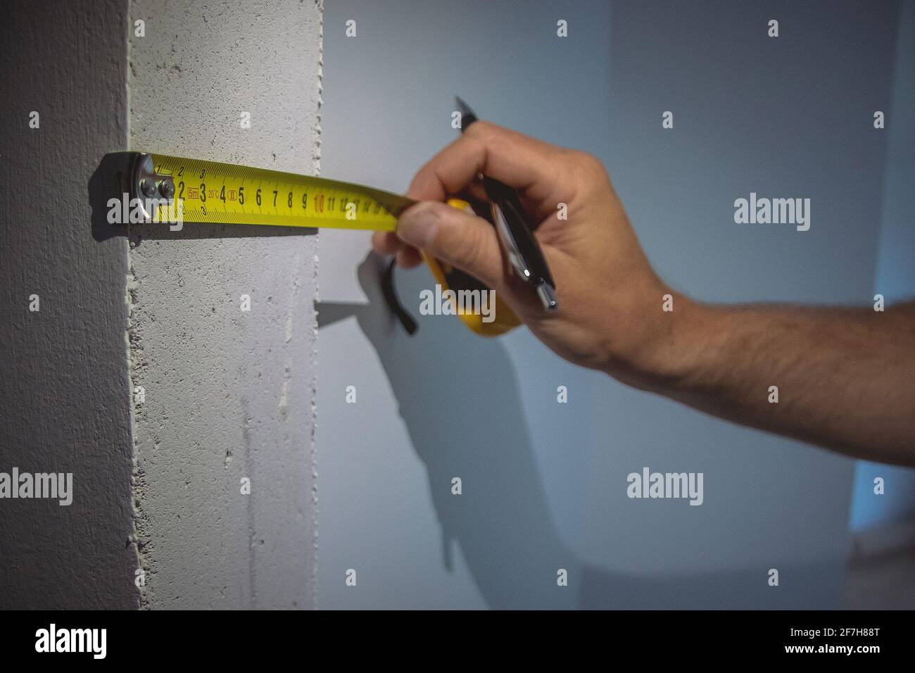 A person measuring width and height of a door opening with a yellow ...
