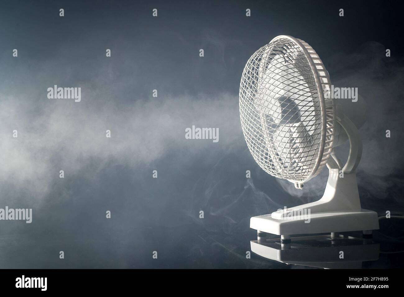 Side view of a white electric desktop fan on a black background and ...