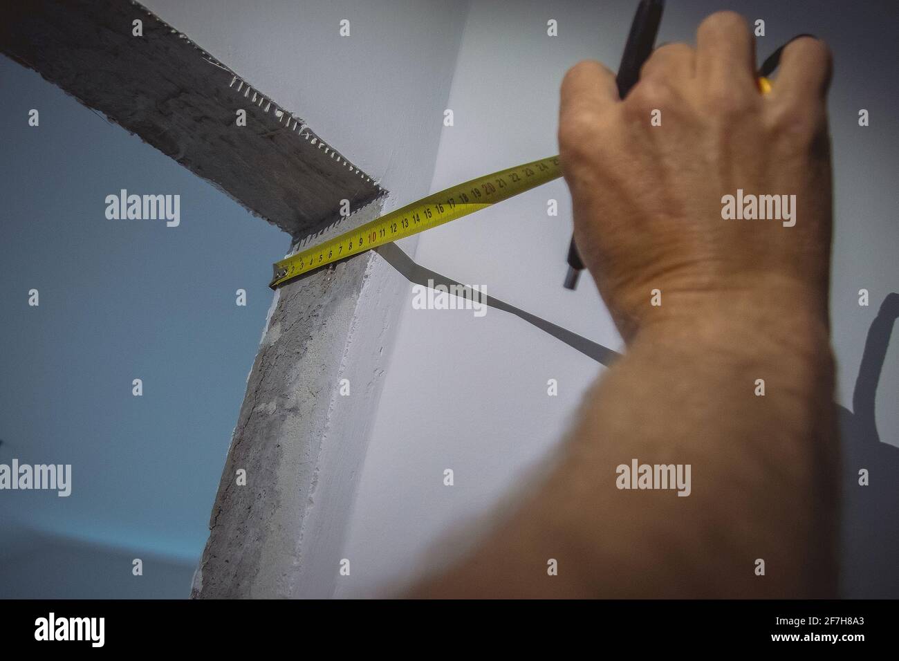 A person measuring width and height of a door opening with a yellow ...