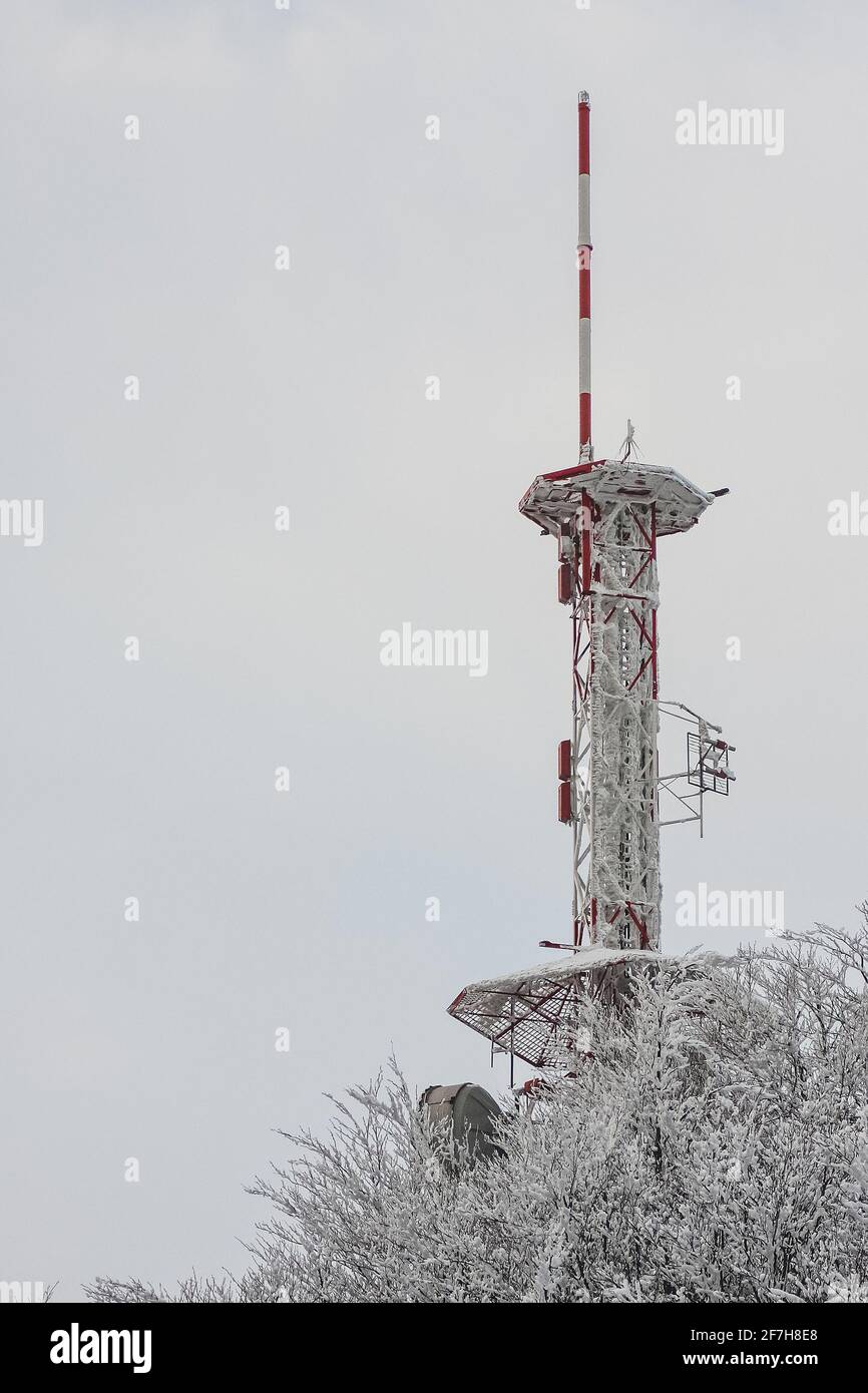 Radio and TV antenna covered with snow and ice on a foggy day in winter ...