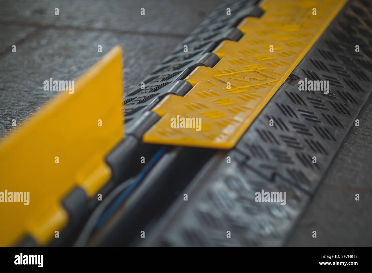 Black and yellow plastic cable protector on the ground. Floor cable ...