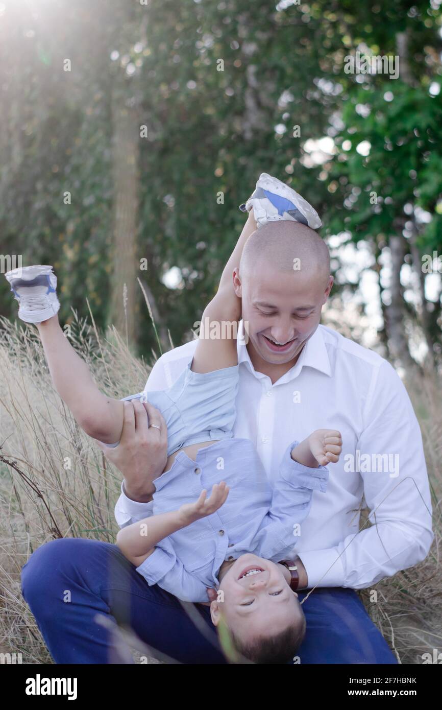 Bald dad and little son in the field or forest on sunny summer day ...