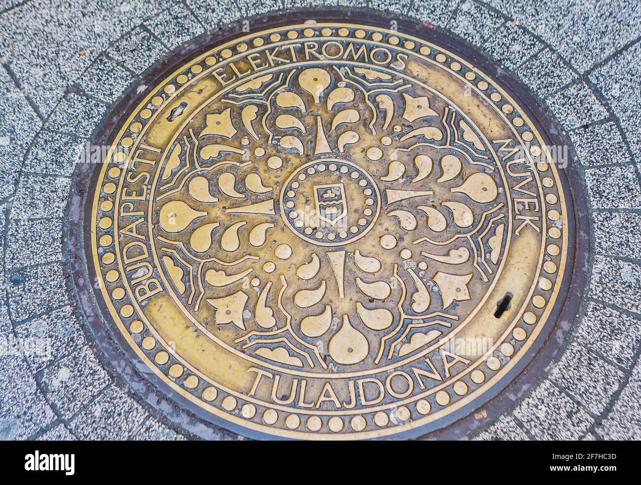 Typical decorative, patterned round brass manhole cover in the street ...