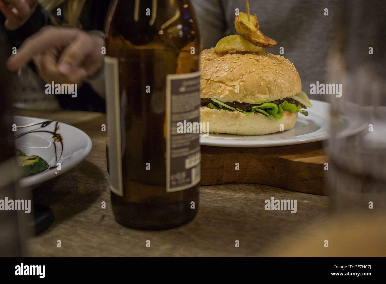 Photo of a burger hiding behind a brown beer bottle. Non staged photo ...