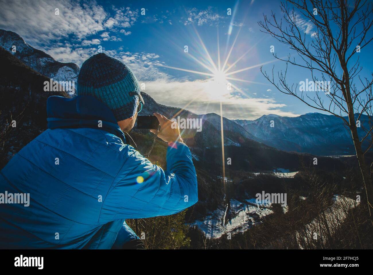 Strong lens flare with a hiker taking a photograph of a valley on ...