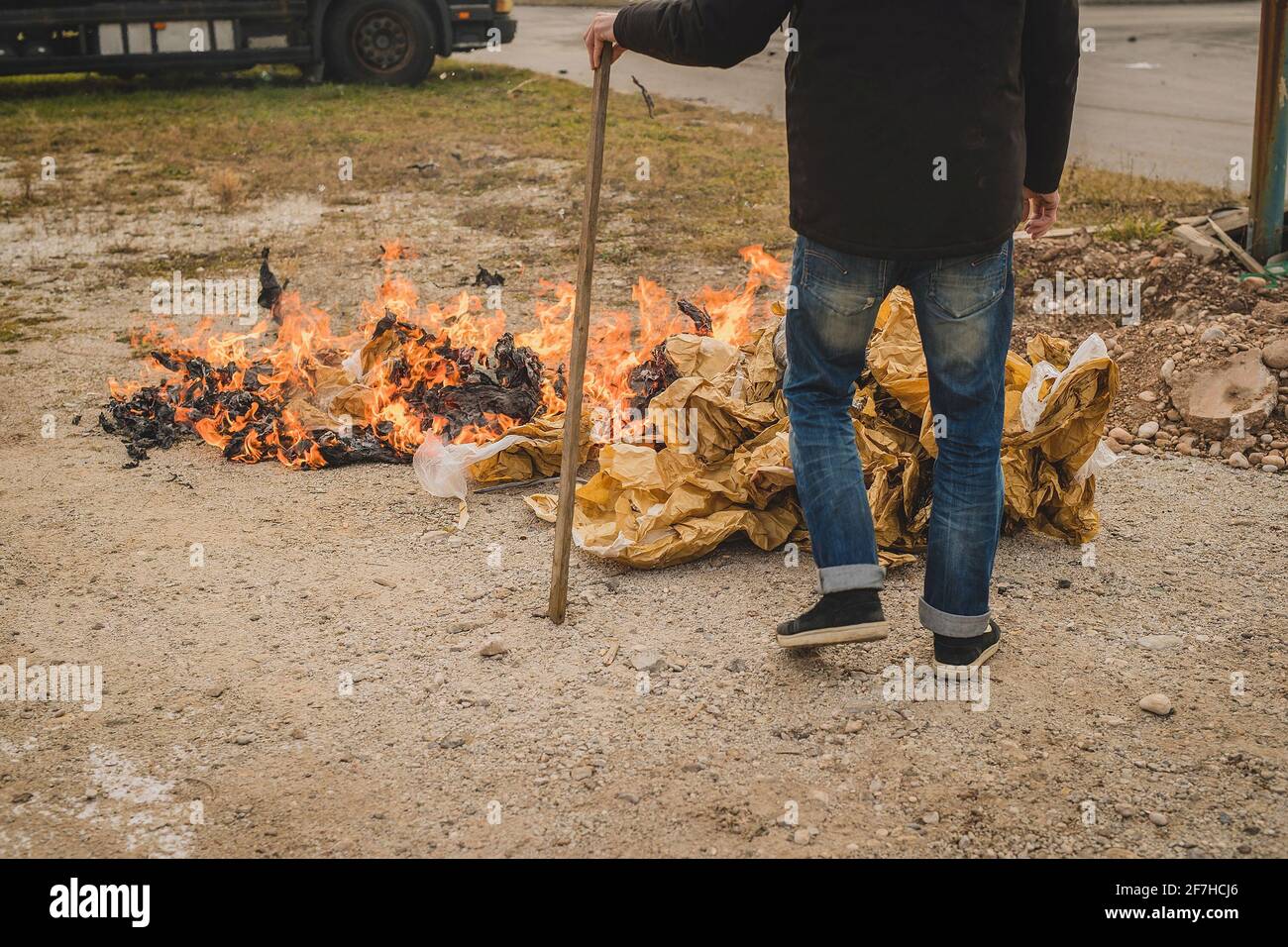 A man is burning a fire out of paper in an open space. Burning paper ...