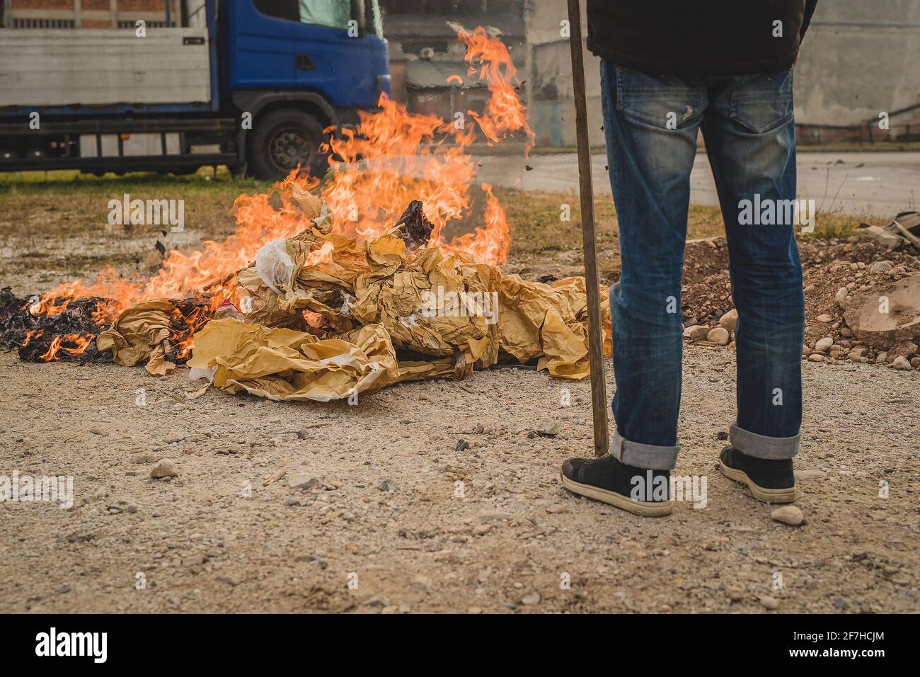 A man is burning a fire out of paper in an open space. Burning paper ...